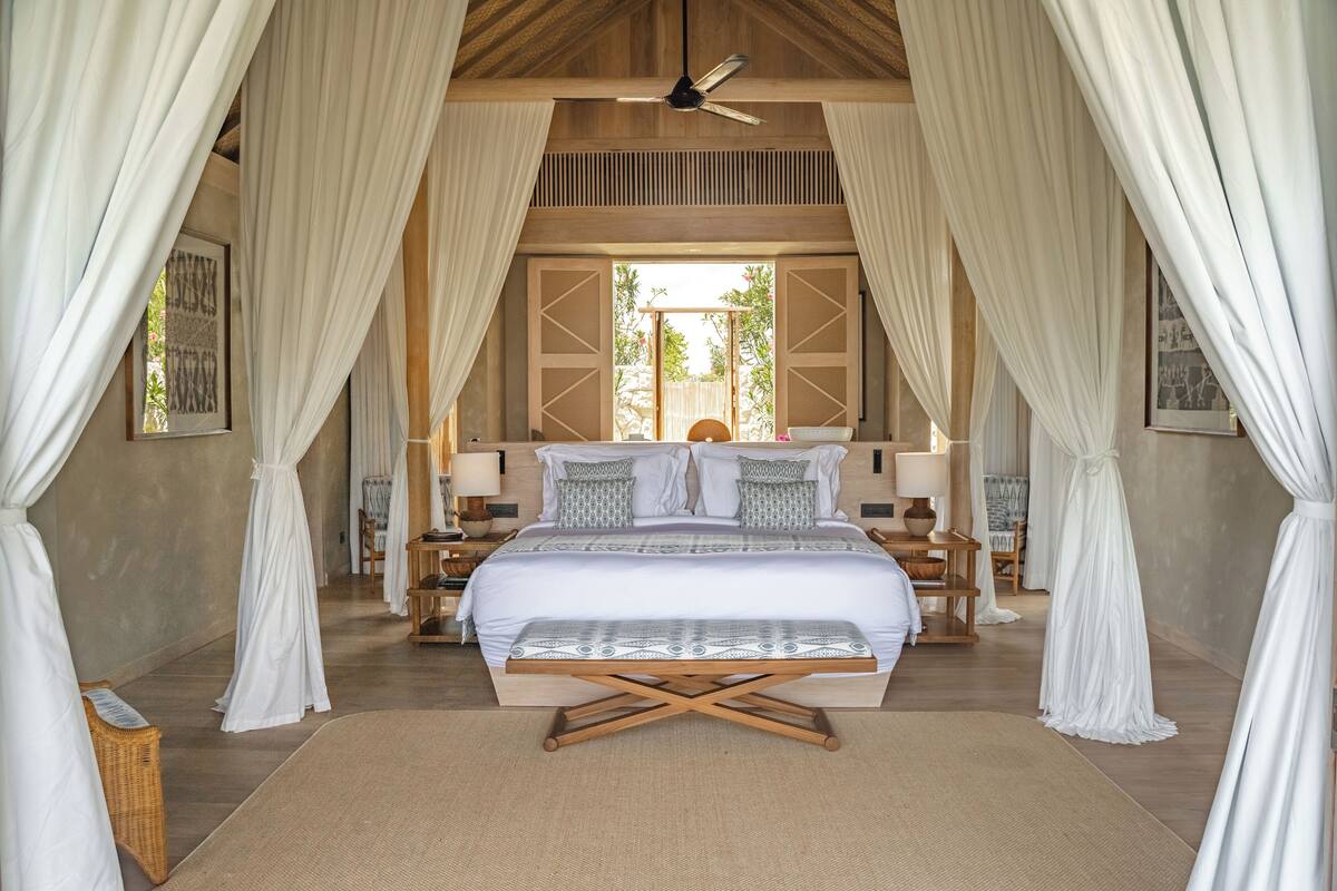 Um quarto espaçoso com uma cama grande, cabeceira de madeira e ventilador de teto.