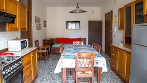 Uma cozinha compacta com armários de madeira, micro-ondas, fogão e mesa de jantar para quatro pessoas.