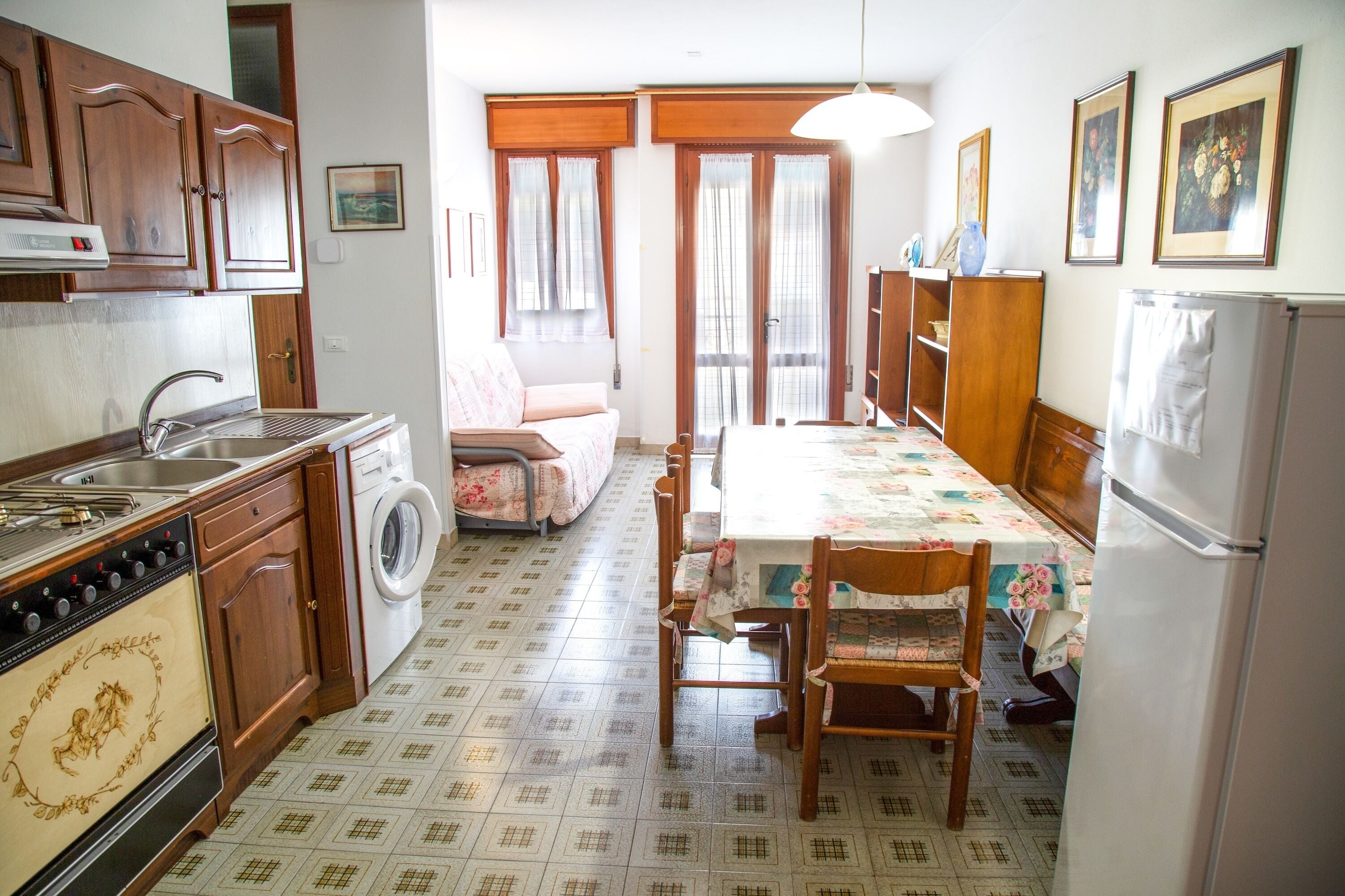 Uma cozinha com armários de madeira, máquina de lavar, mesa de jantar com cadeiras e geladeira.