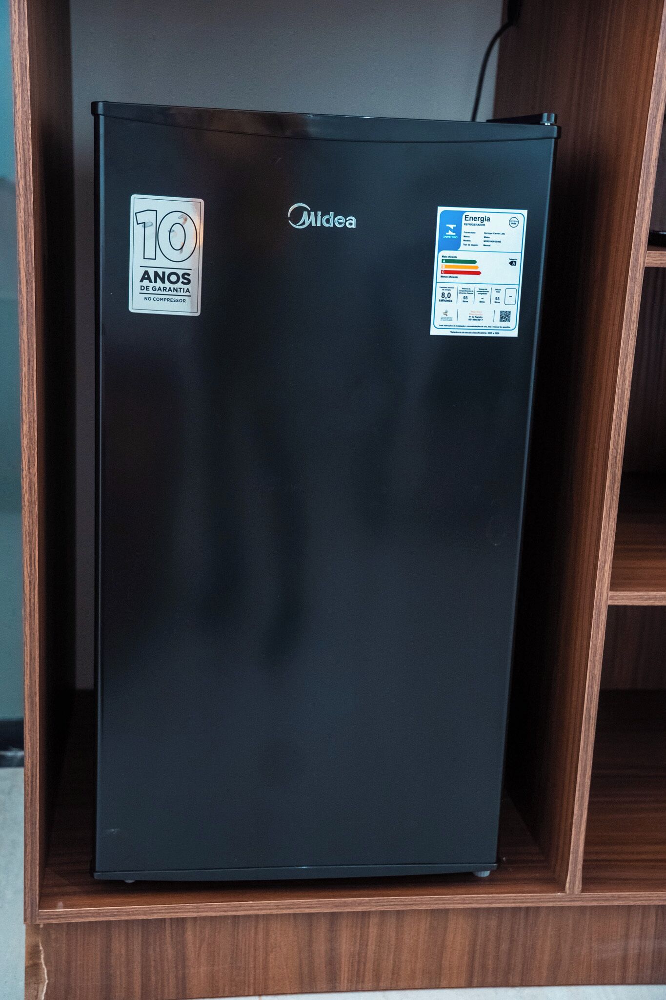 Uma geladeira preta com etiqueta de '10 anos de garantia' e etiqueta de eficiência energética.