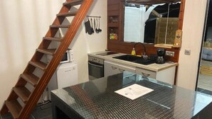 Cozinha compacta com escada de madeira, micro-ondas, cafeteira e mini-geladeira.
