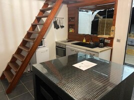 Cozinha compacta com escada de madeira, micro-ondas, cafeteira e mini-geladeira.