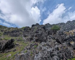 Paisagem vulcânica acidentada com terreno rochoso e vegetação escassa.