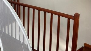 Uma escada com corrimãos de madeira e um aparelho de ar condicionado fixado na parede acima.