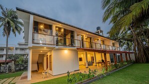 Uma casa moderna de dois andares com varanda, um gramado bem cuidado e um muro de pedra.