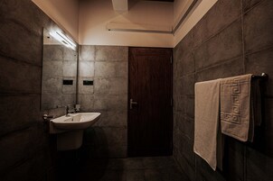 Uma casa de banho com lavatório, espelho e porta-toalhas.
