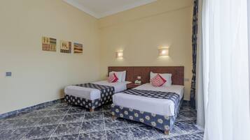 Quarto de hotel com duas camas, piso de mármore e luminárias fixadas na parede.