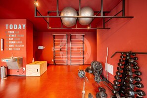 Uma academia com equipamentos de exercícios, uma caixa de madeira e uma frase motivacional na parede.