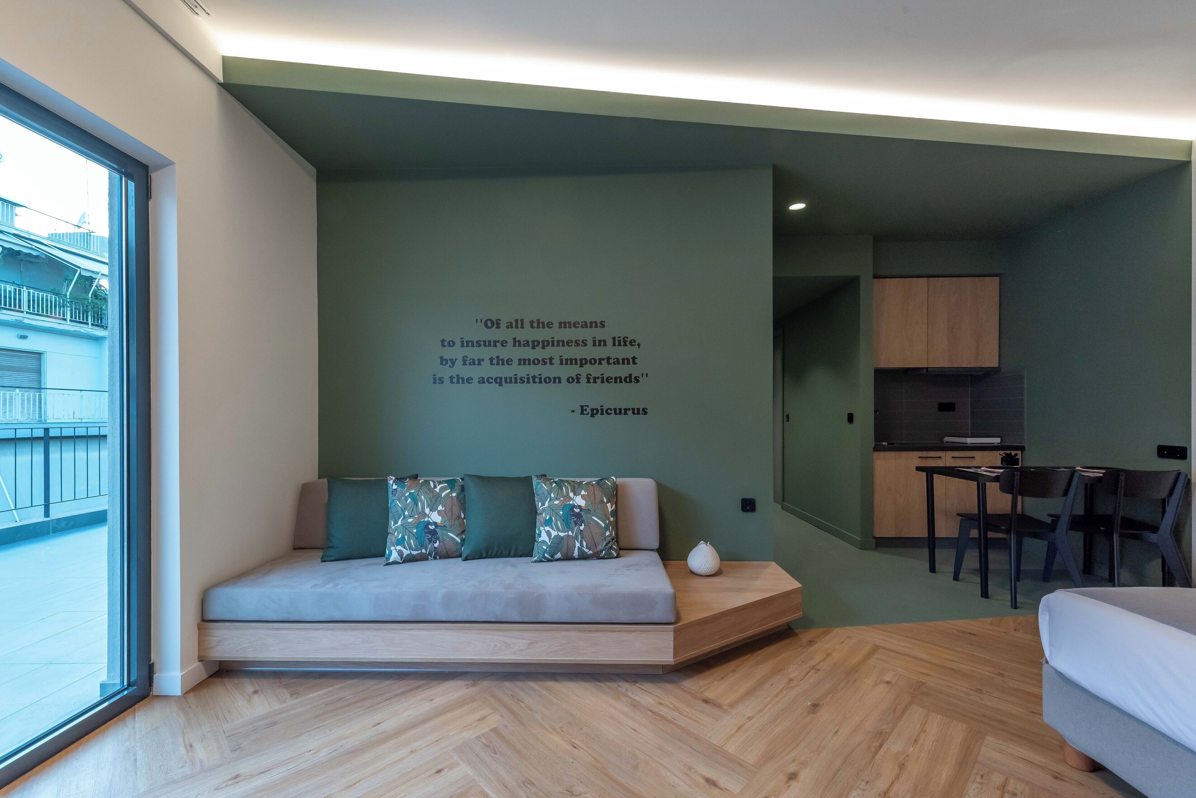Uma sala de estar moderna com um sofá, uma citação na parede e vista para o exterior.