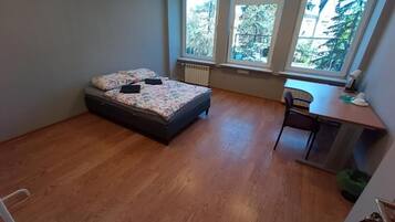Um quarto com cama, escrivaninha e cadeira.