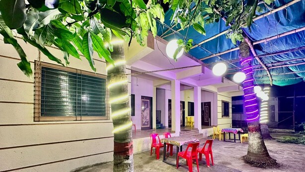 Uma área externa com mesas e cadeiras, um espaço coberto para sentar e um edifício com janelas e portas.