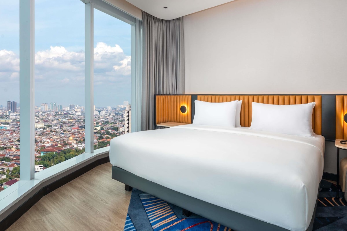 Quarto de hotel com uma cama grande, vista para a cidade e design moderno.