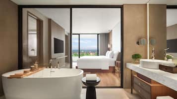 Uma casa de banho de hotel moderna, com uma banheira grande, uma toucador com espelho e uma cama com vista para a cidade.