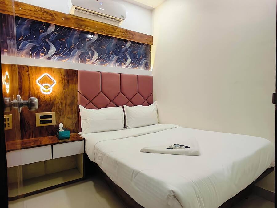 Quarto moderno com cama grande, ventoinha no teto, ar condicionado e um painel decorativo na parede.