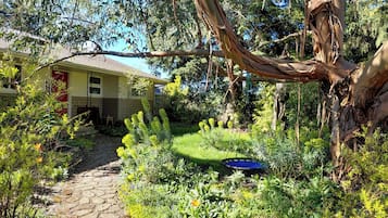 Um jardim com um caminho de pedra, um balanço e uma casa com porta vermelha.