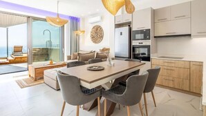 Cozinha moderna com área de refeições, janelas amplas e vista para o mar.
