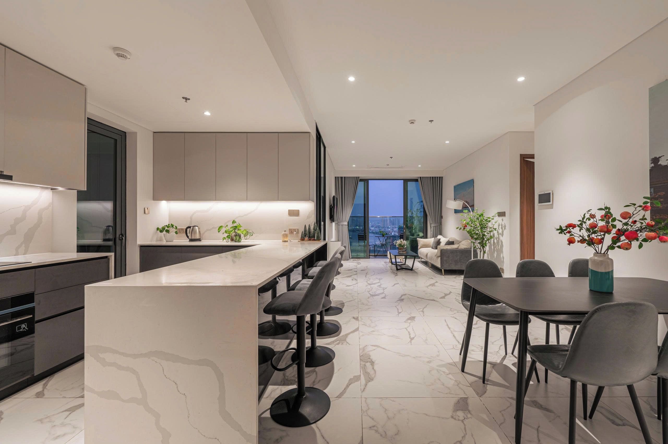 Cozinha moderna com ilha central, banquetas de bar e área de jantar com mesa e cadeiras.