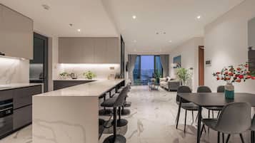 Cozinha moderna com ilha central, banquetas de bar e área de jantar com mesa e cadeiras.