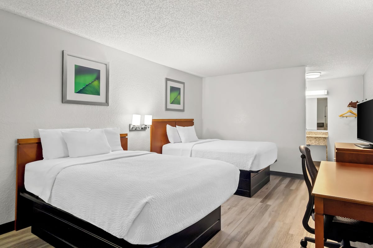Quarto de hotel com duas camas, uma escrivaninha e uma televisão.