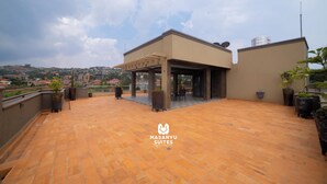 Terraço no telhado com pérgola, área de estar e plantas em vasos.