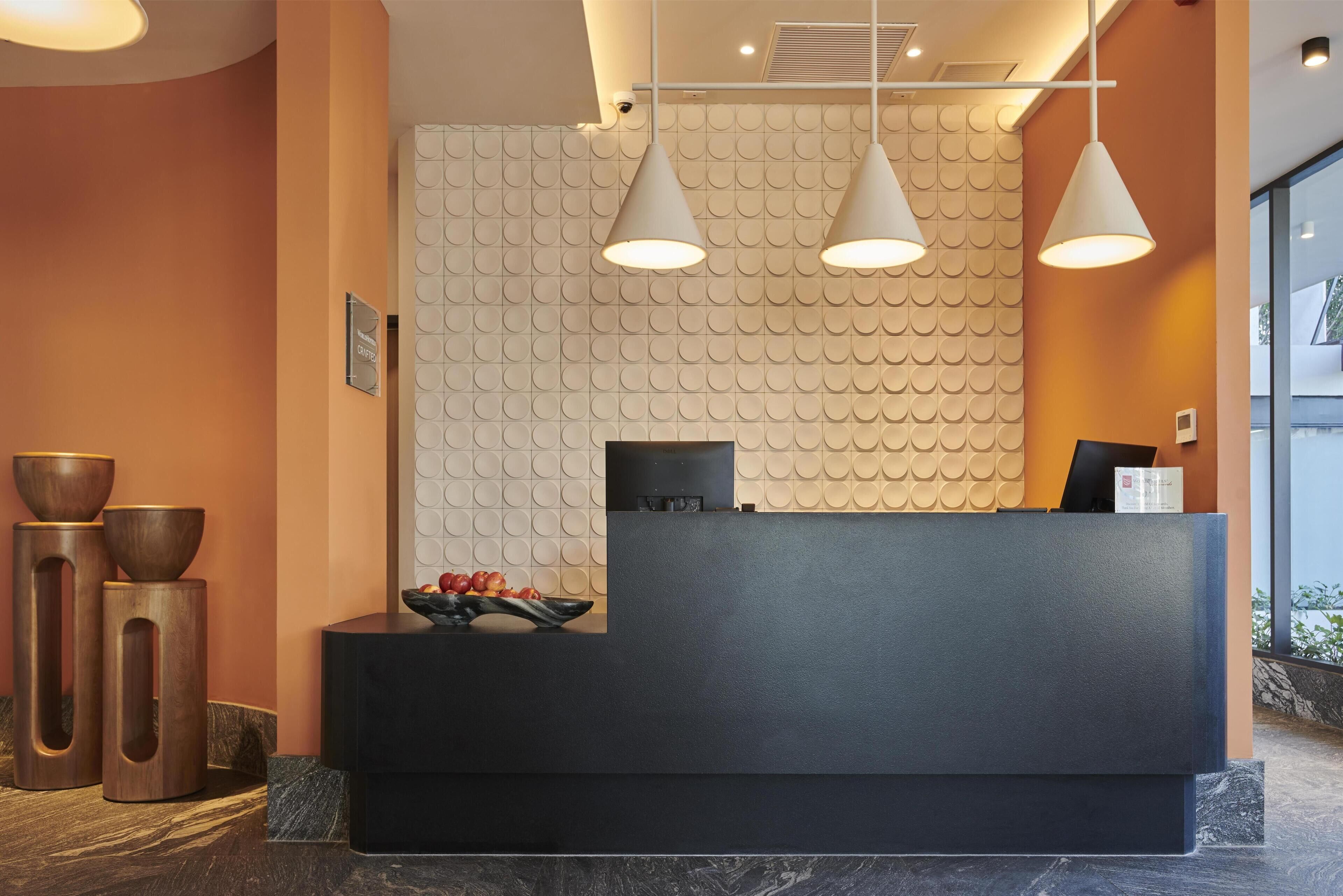 Um balcão de recepção com design moderno, com um tampo preto e um painel de parede padronizado atrás.