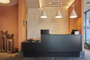 Um balcão de recepção com design moderno, com um tampo preto e um painel de parede padronizado atrás.