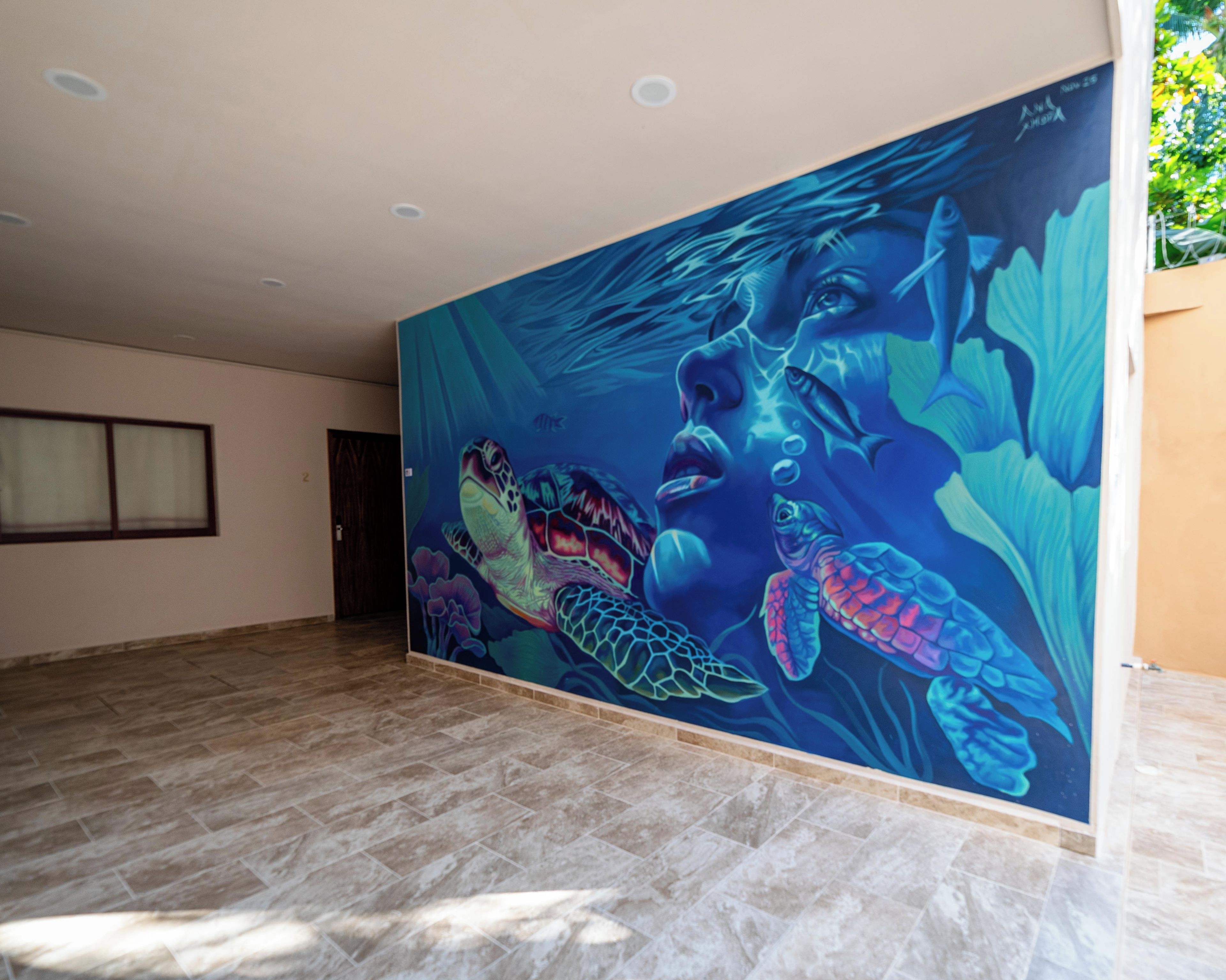 Quarto espaçoso com um grande mural de criaturas marinhas na parede.