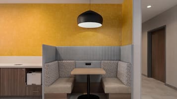 Uma área de estar nos cantos, com uma mesa e cadeiras, uma luminária pendente e uma parede com textura.