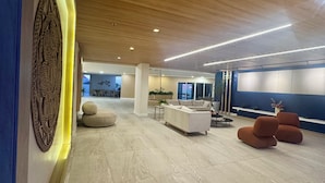 Um hall amplo com teto de madeira, uma grande obra de arte na parede e uma área de estar com sofás e mesa de centro.