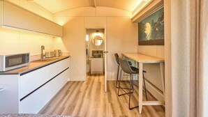 Uma cozinha compacta com eletrodomésticos modernos, uma área de jantar com uma cadeira e um quadro na parede.