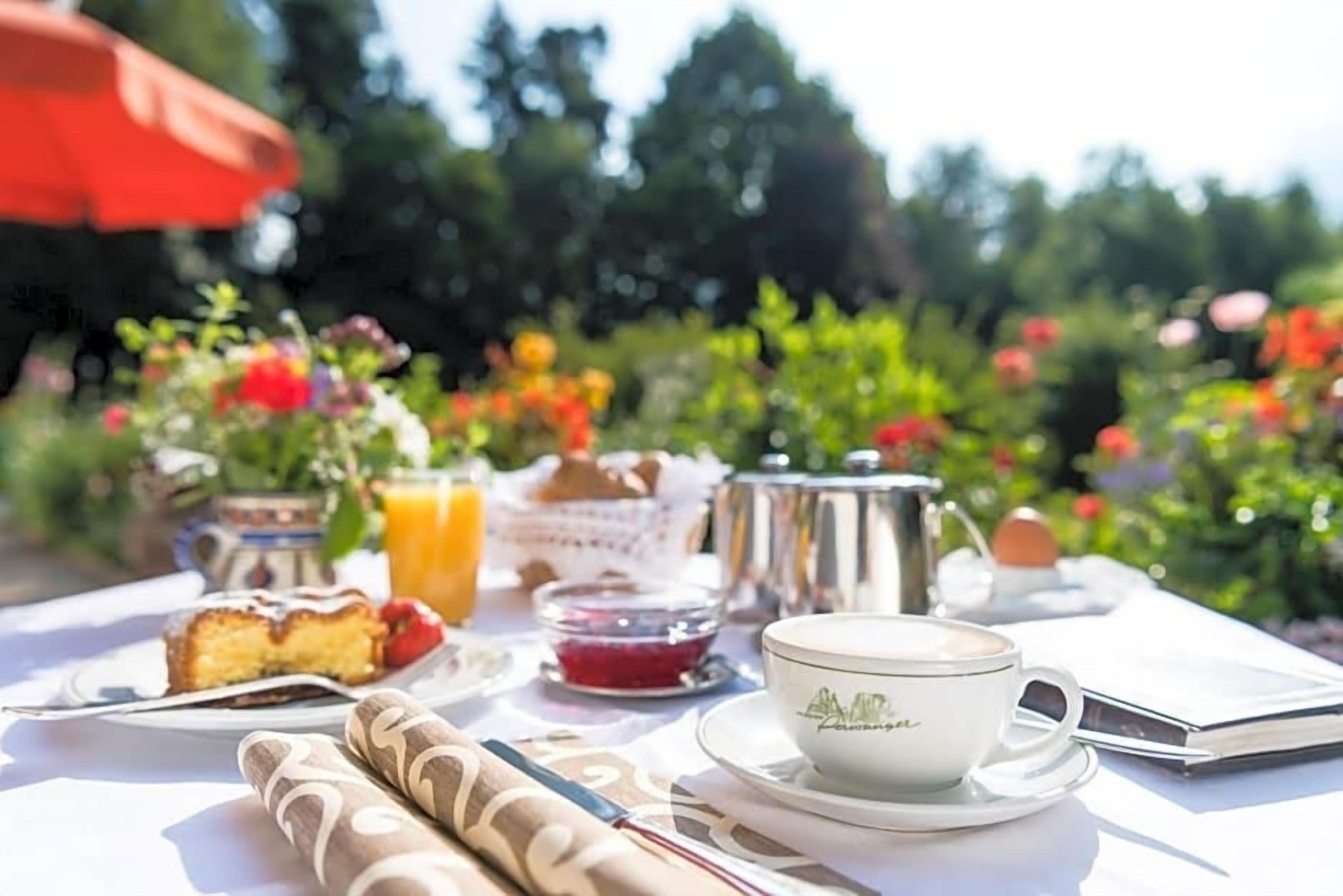 Disposição para refeições ao ar livre com uma mesa, uma xícara de café, um pastel e uma saladeira de frutas.