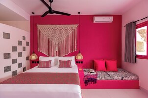 Quarto com cama, um pequeno sofá, um painel de macramé na parede e um ar condicionado.