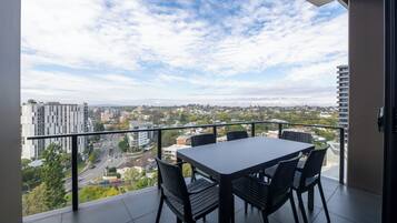 Varanda com mesa e cadeiras, com vista para a cidade.