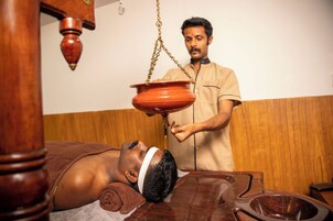 Uma pessoa recebendo um tratamento tradicional num quarto com paredes de madeira e uma cama.