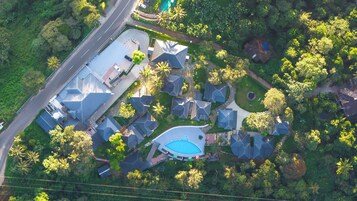 Vista aérea de um bairro residencial com várias casas, piscina e uma estrada.
