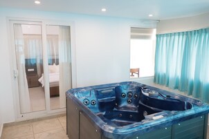 Uma casa de banho moderna com uma banheira grande, uma porta de correr de vidro que dá para um quarto e vista para uma varanda.