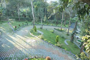 Um parque com calçada pavimentada, bancos e vegetação exuberante.