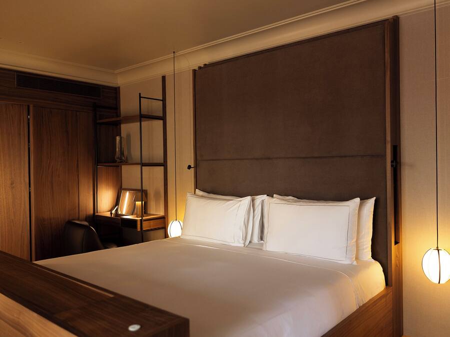 Quarto de hotel com cama grande, mesas de cabeceira, escrivaninha e guarda-roupa.