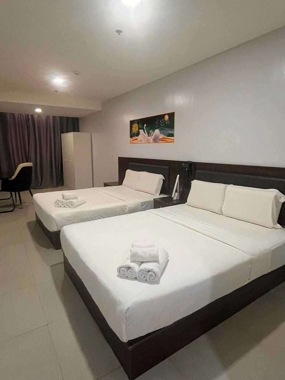 Quarto de hotel com duas camas, uma escrivaninha e uma cadeira.