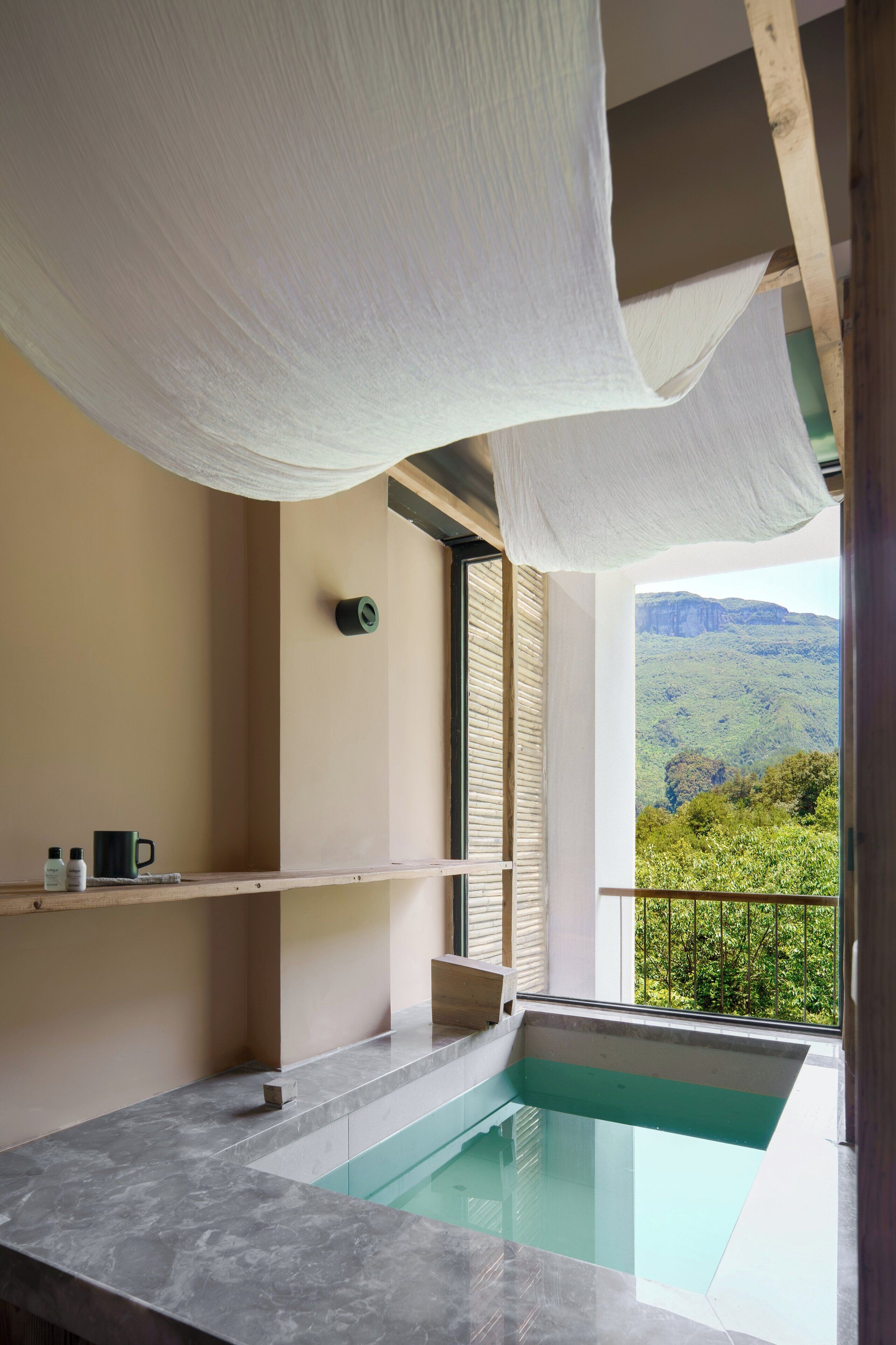 Um banheiro moderno com uma janela ampla, bancada de mármore e vista para uma paisagem montanhosa.
