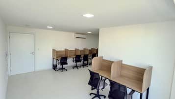 Uma sala de conferências com várias estações de trabalho, paredes brancas e chão de azulejos.