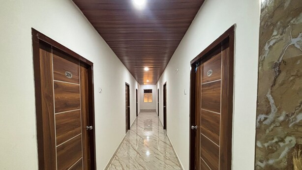 Um corredor com portas de madeira, piso de mármore e teto de madeira.