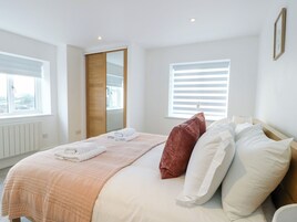 Quarto com cama, almofadas e janela.