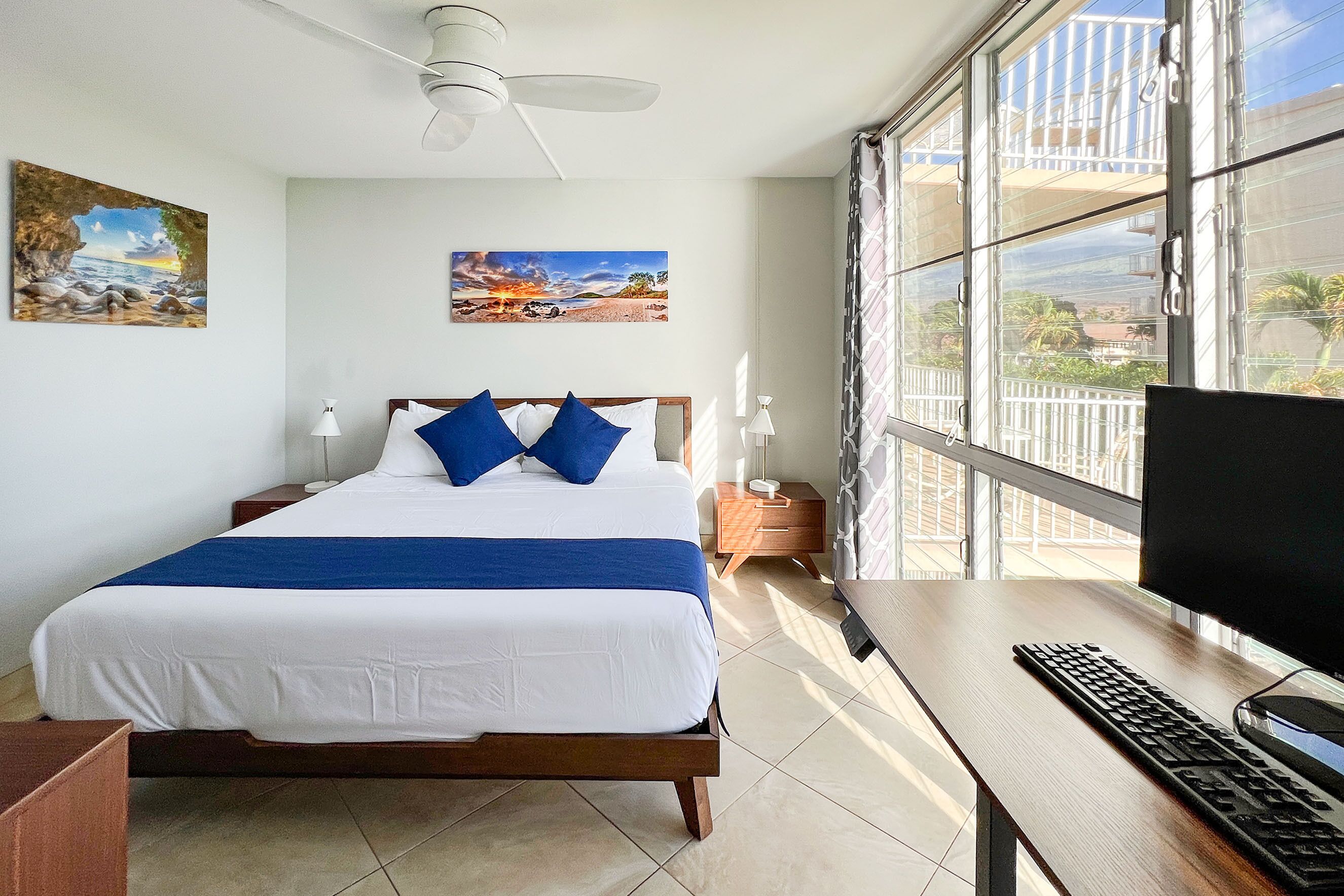 Quarto com cama, escrivaninha, televisão e janela com vista.