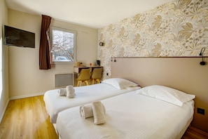 Quarto de hotel com duas camas, uma escrivaninha e uma cadeira.