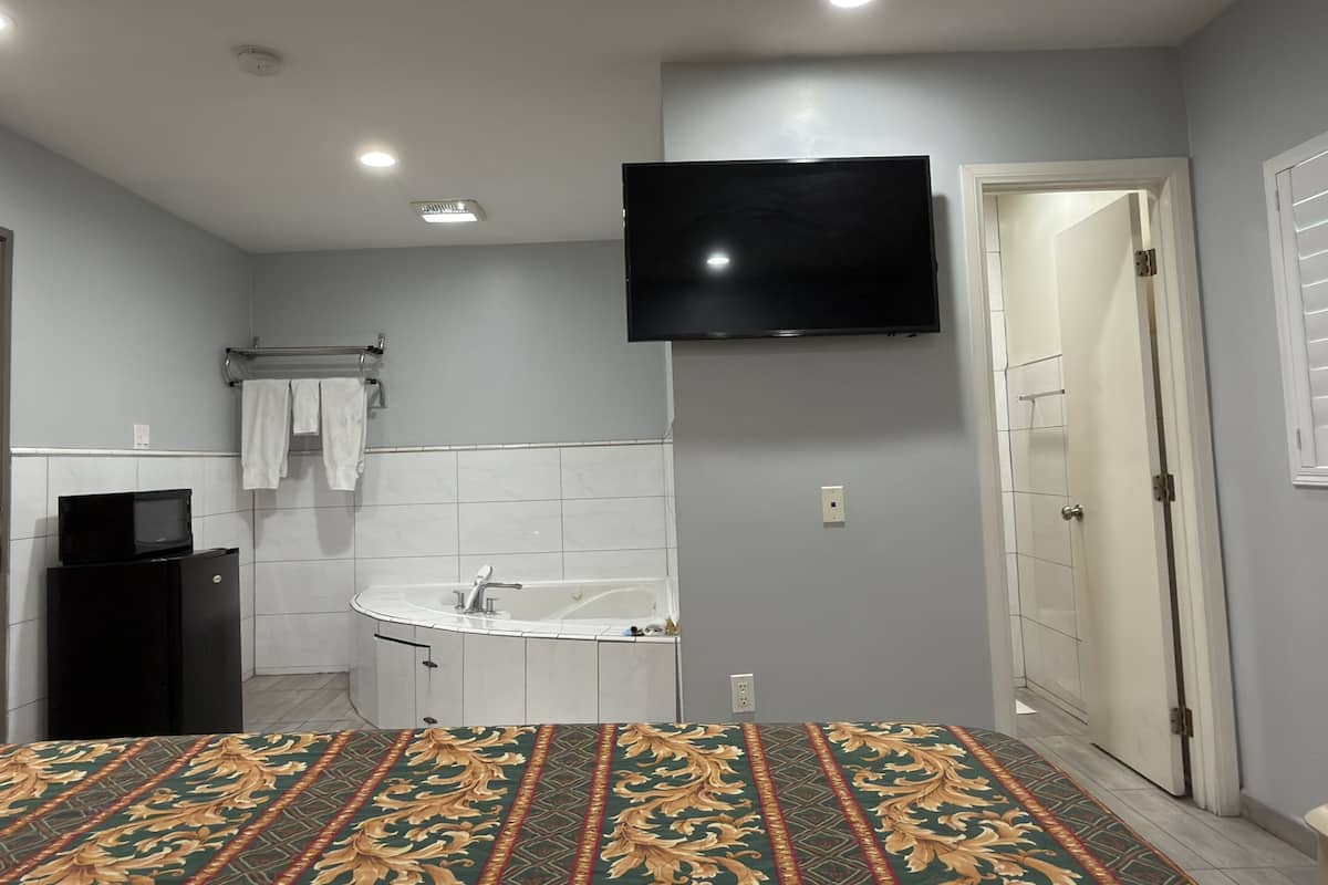 Casa de banho com lavatório, espelho e televisão fixada na parede.