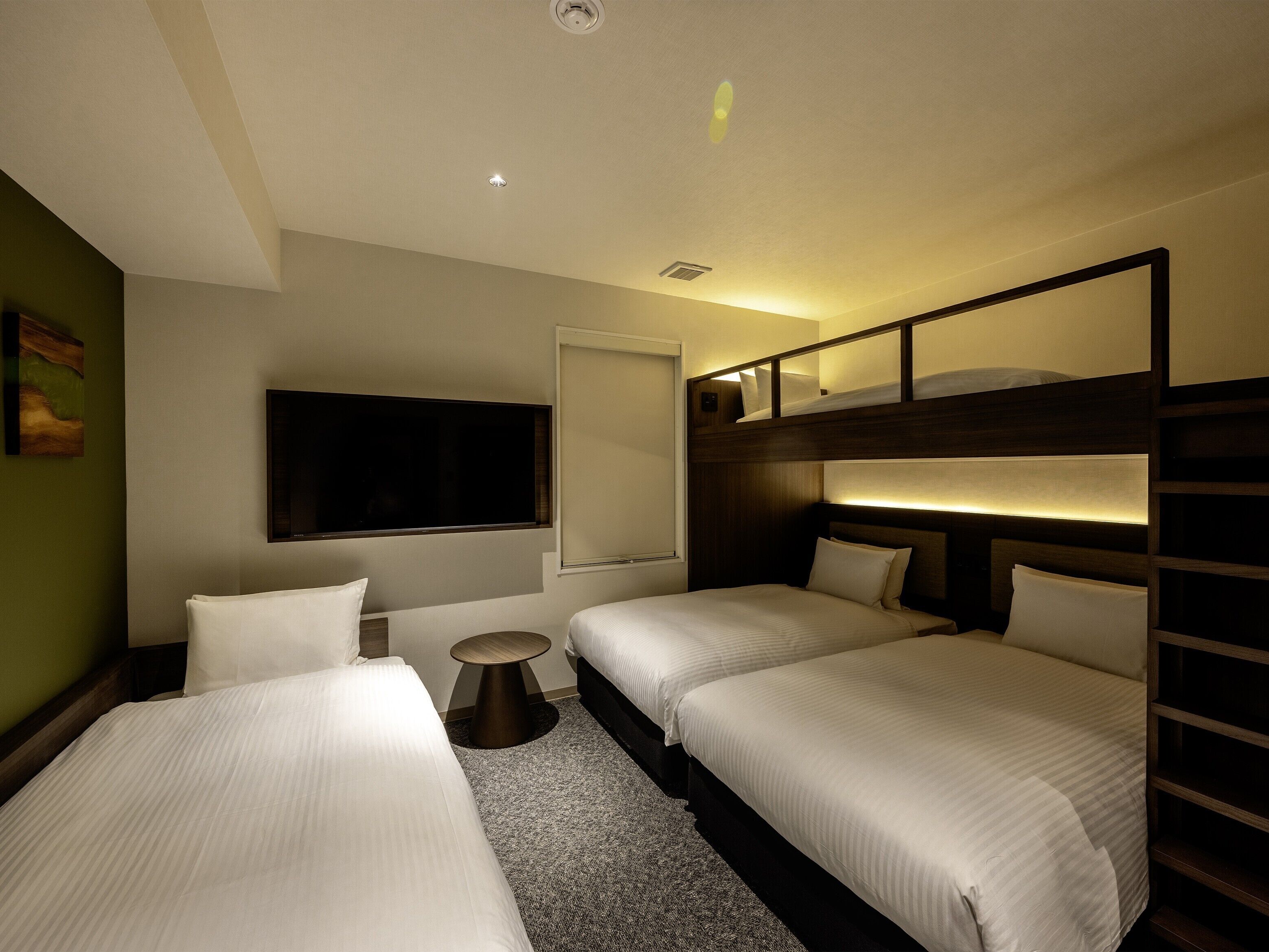 Quarto de hotel com duas camas, televisão, mesa redonda pequena e janela.
