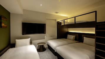 Quarto de hotel com duas camas, televisão, mesa redonda pequena e janela.