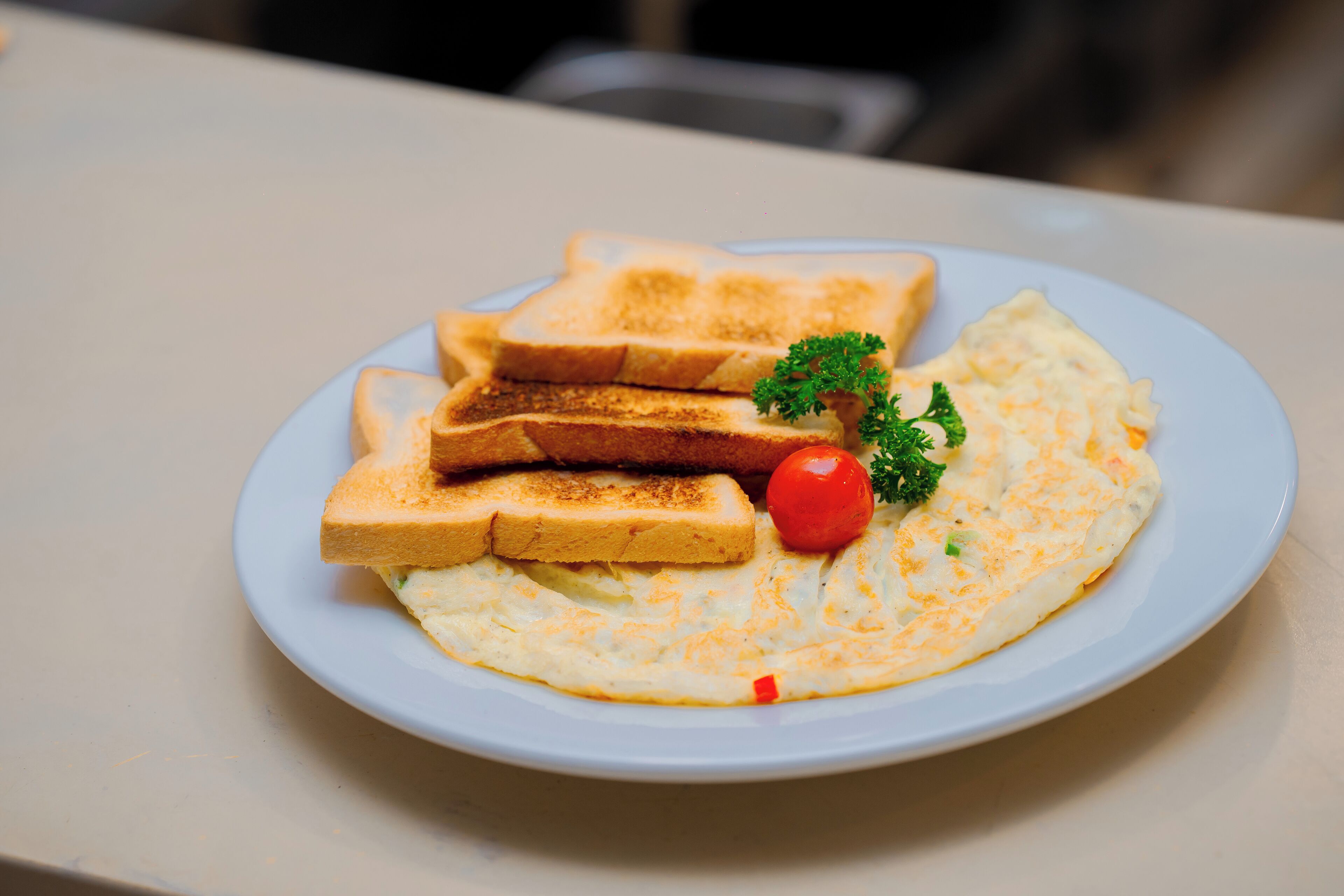 Prato com torrada e omelete sobre uma mesa.