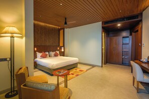 Quarto de hotel com cama, abajur, cadeira, escrivaninha e guarda-roupa.